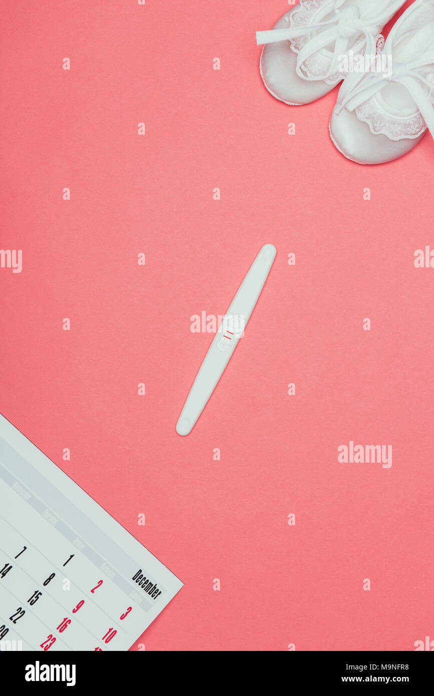 top view of childish shoes, pregnancy test and calendar isolated on ...