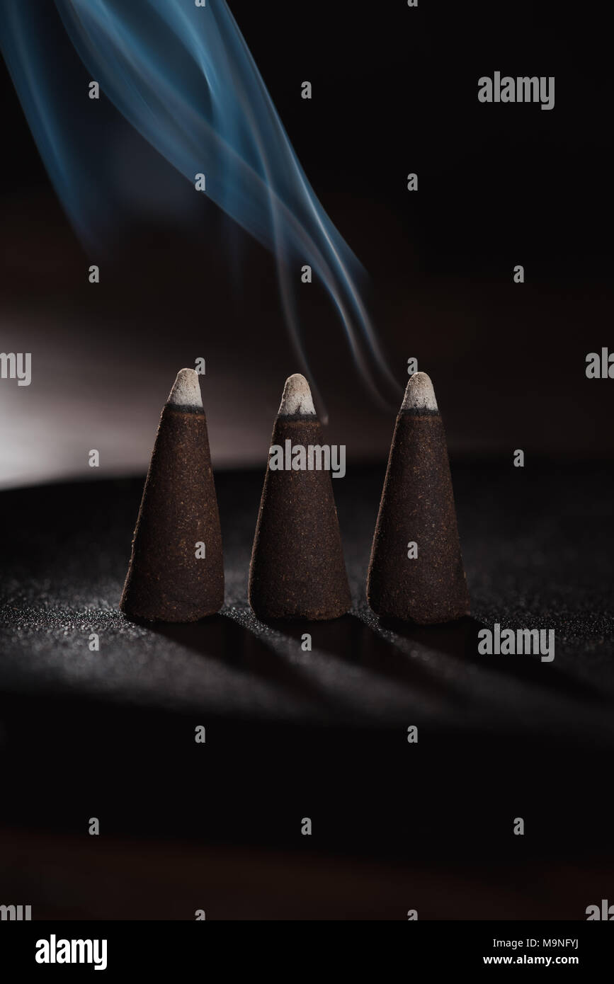 three burning incense sticks with blue smoke on black Stock Photo - Alamy