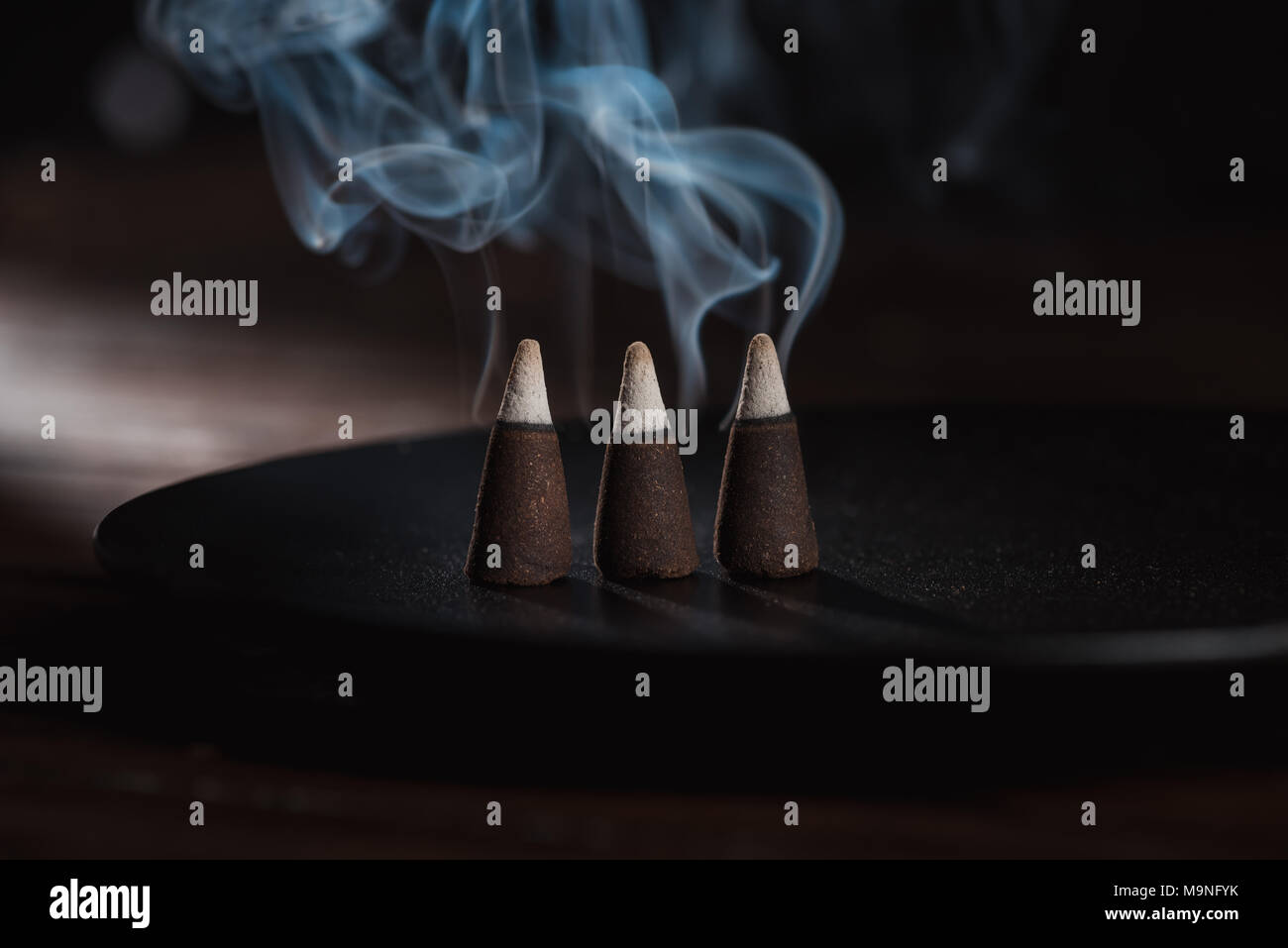 three burning incense sticks with blue smoke Stock Photo - Alamy