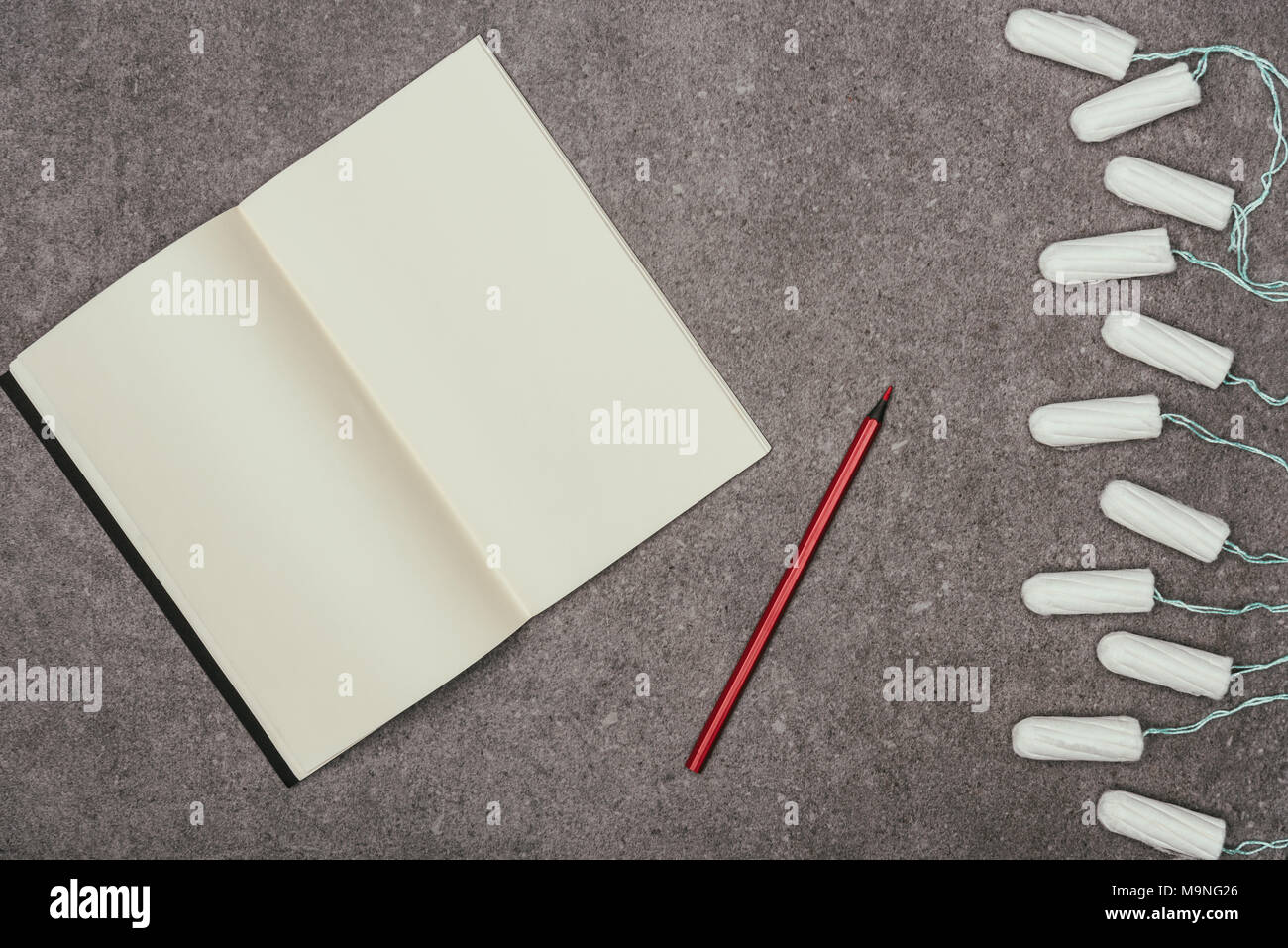 top view of empty notebook, marker and menstrual tampons on grey ...