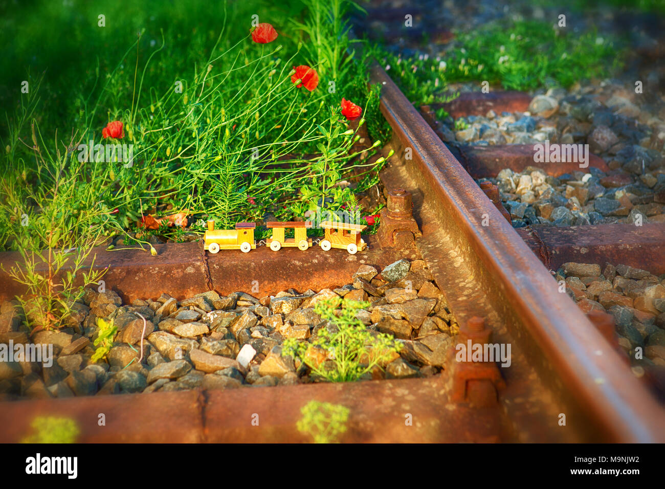small wooden toy train on real railway tracks Stock Photo - Alamy