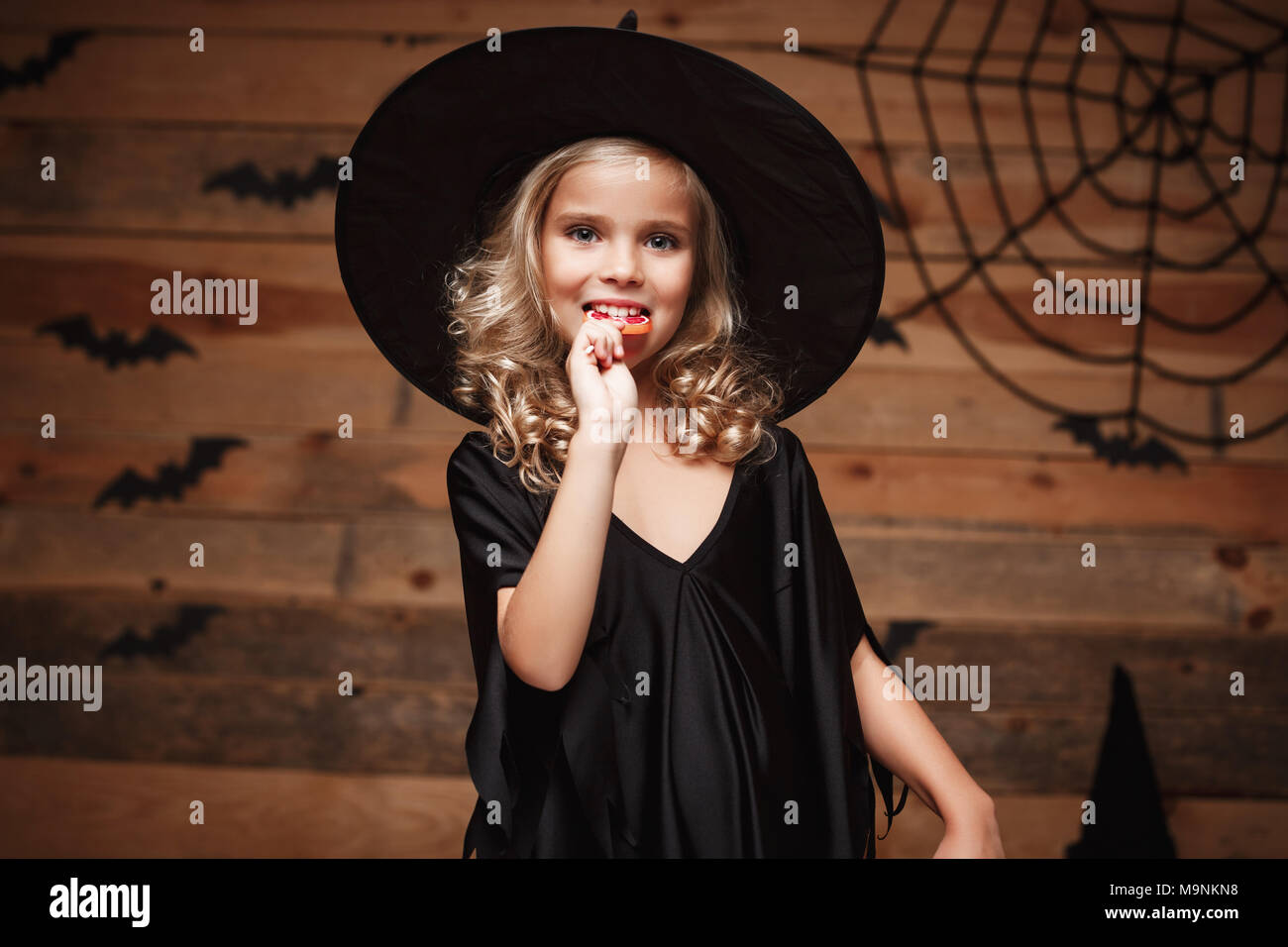 Halloween Witch concept - little witch child with halloween sweet and ...