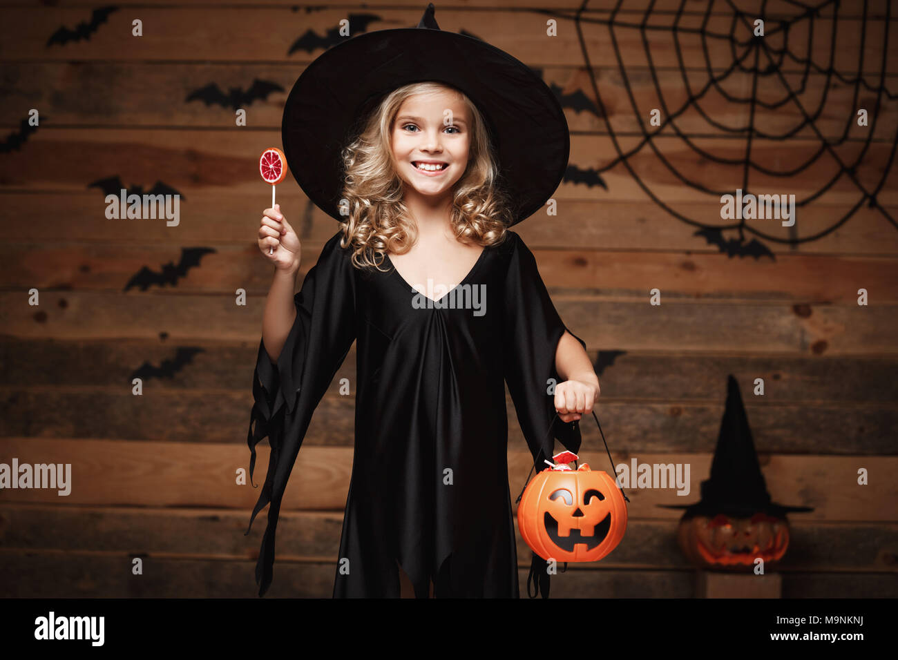 Halloween Witch concept - little witch child with halloween sweet and ...