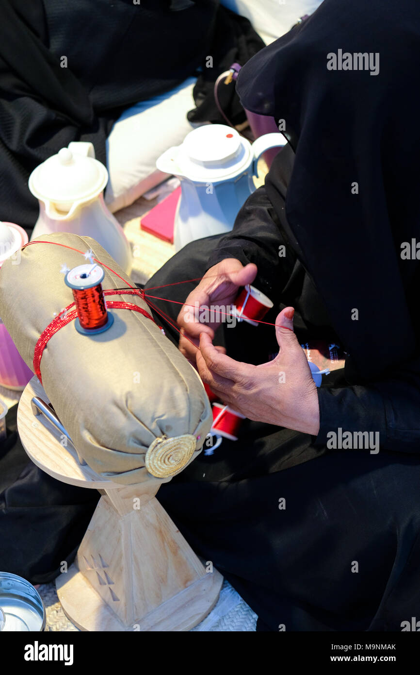 Emirati Bedouin woman wearing traditional black dress making embroidery ...