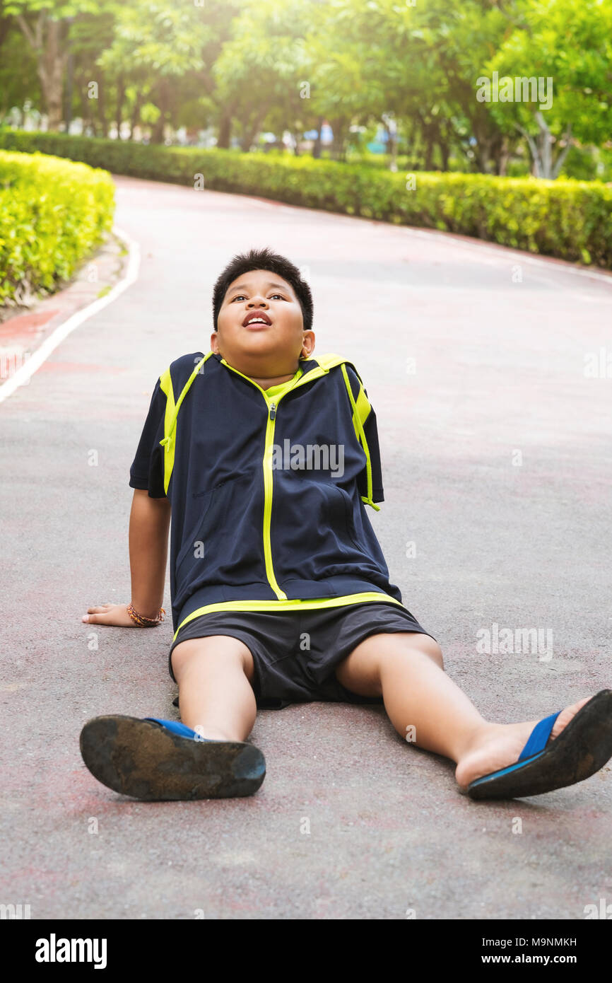 Selective focus at young Asian boy sit and tired on track after running ...