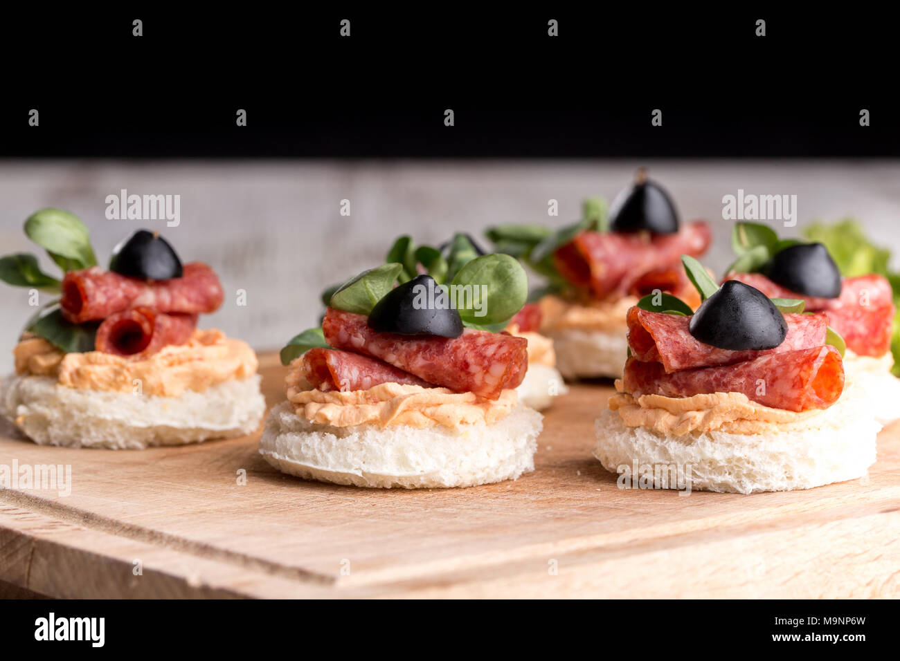 Delicious canapes with salami and spices on a wooden background Stock ...