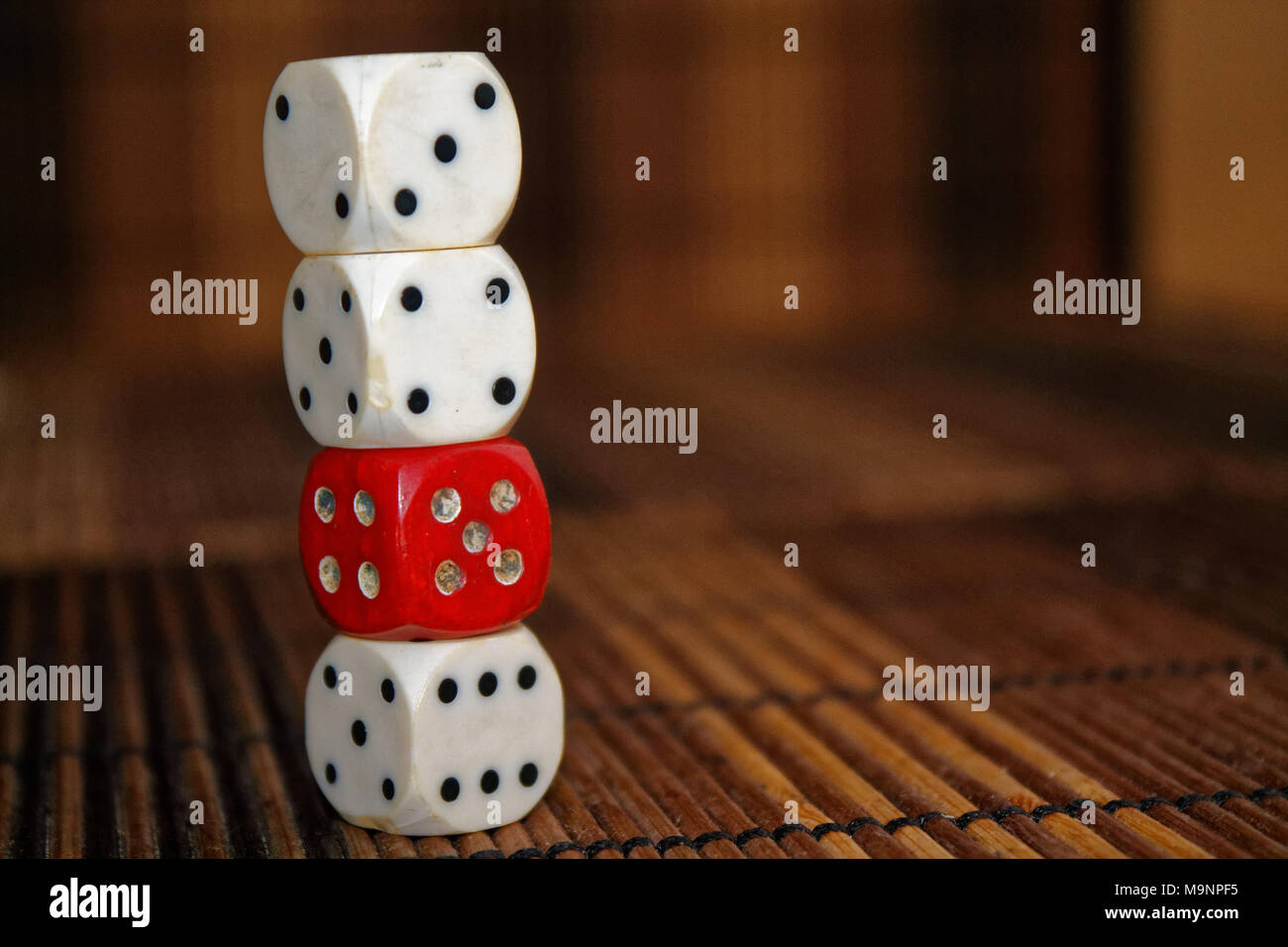 Stack of three white plastic dices and one red dice on brown wooden ...