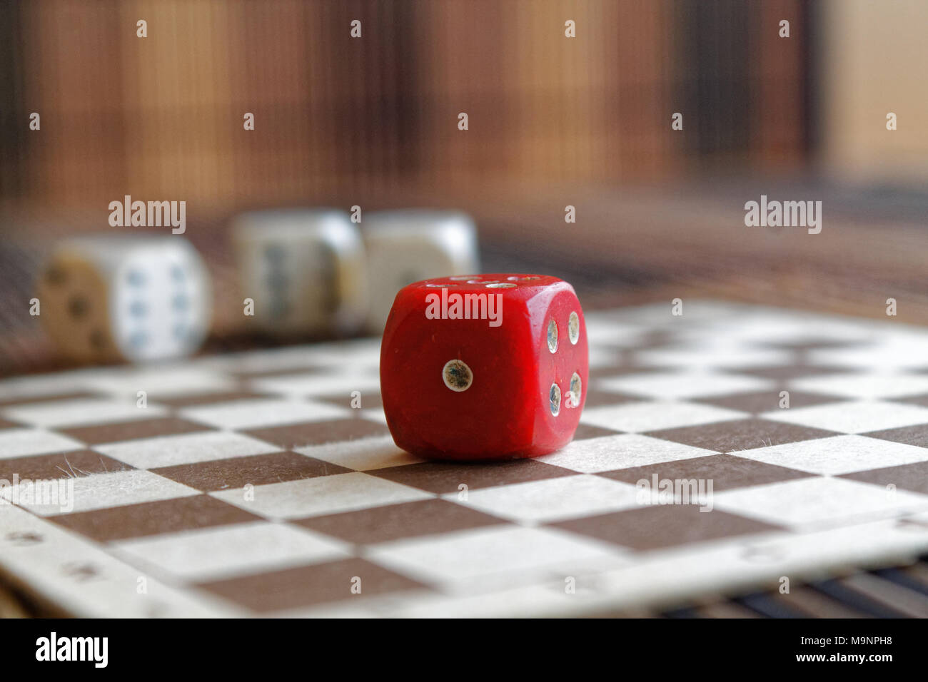 Stack of three white plastic dices and one red dice on brown wooden ...