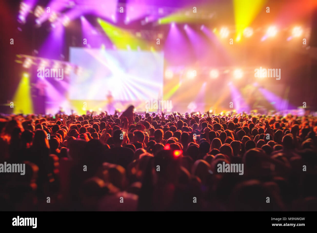 A crowded concert hall with scene stage lights, rock show performance ...