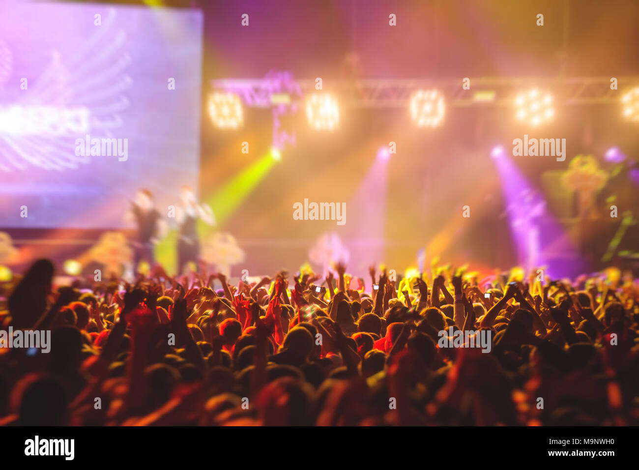 A crowded concert hall with scene stage lights, rock show performance ...