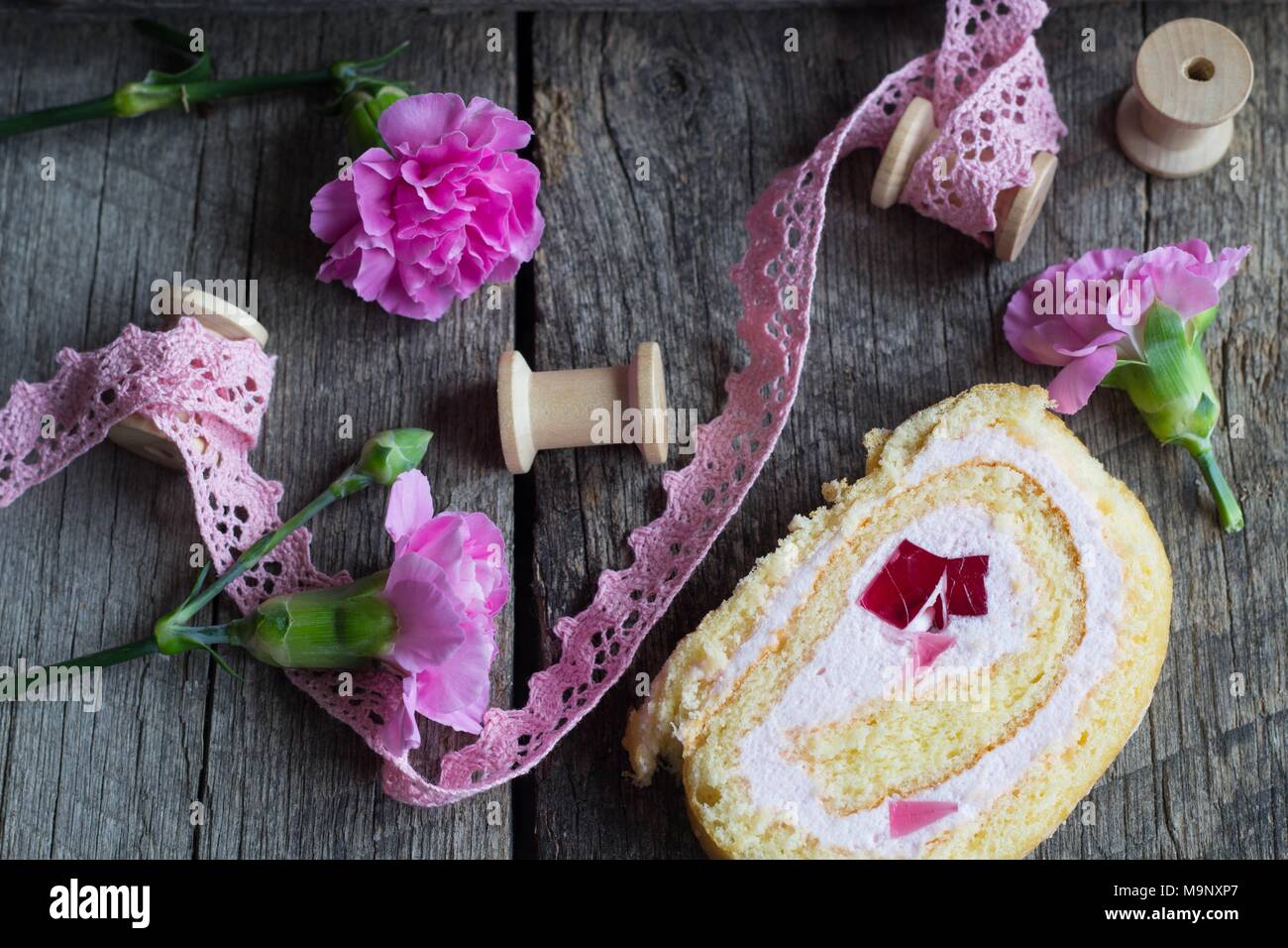 dough biscuit roll, wooden bobbins and pink carnation flowers on wooden ...