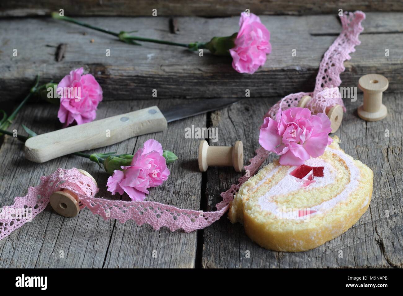dough biscuit roll, wooden bobbins and pink carnation flowers on wooden ...