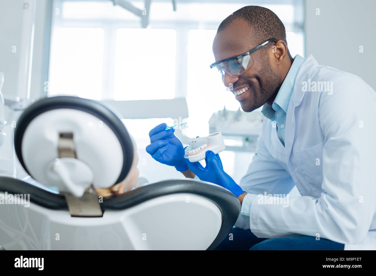 Pleasant male dentist talking about proper teeth care Stock Photo - Alamy