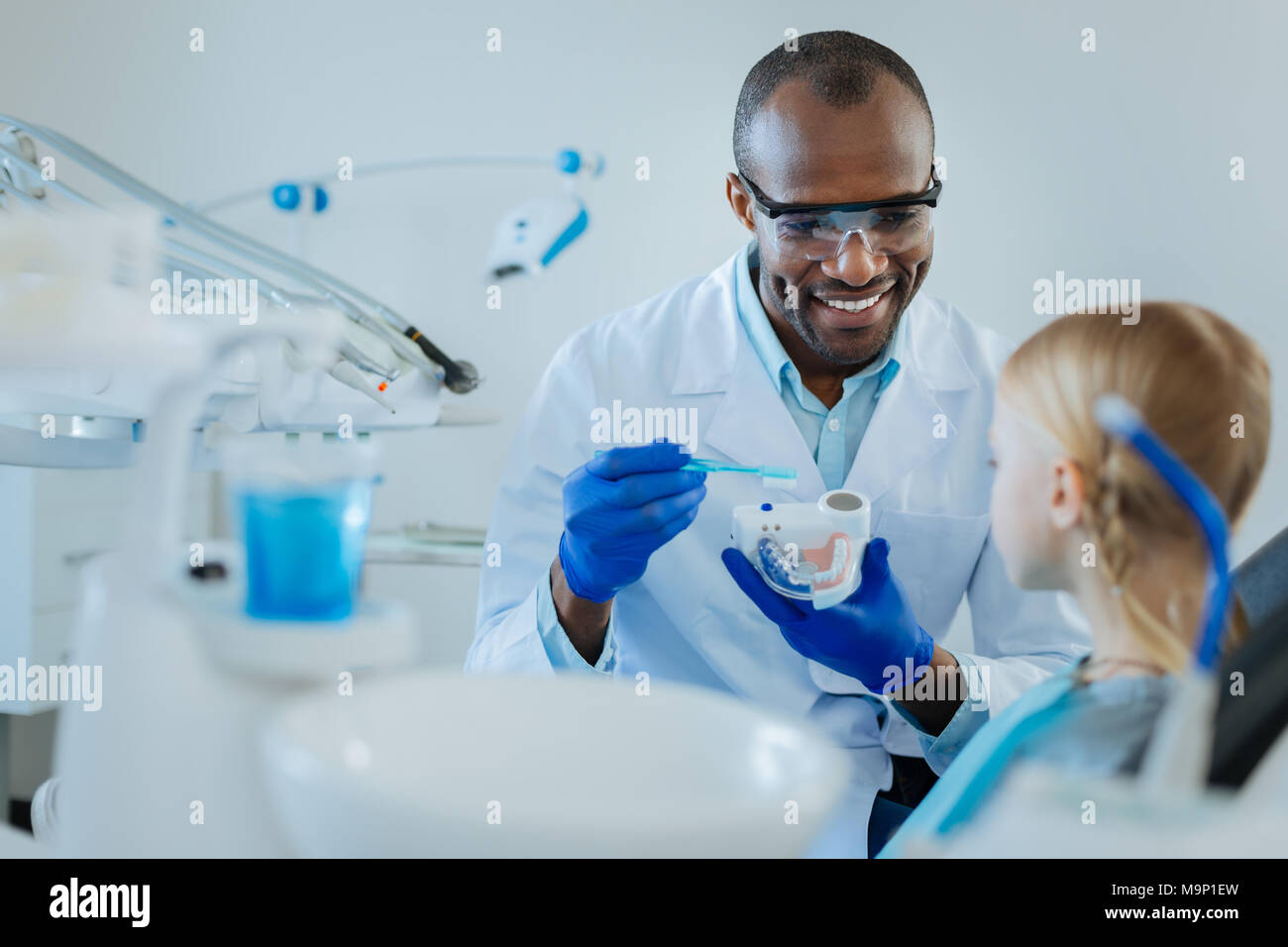 Smiling dentist telling teeth care tips to his patient Stock Photo - Alamy