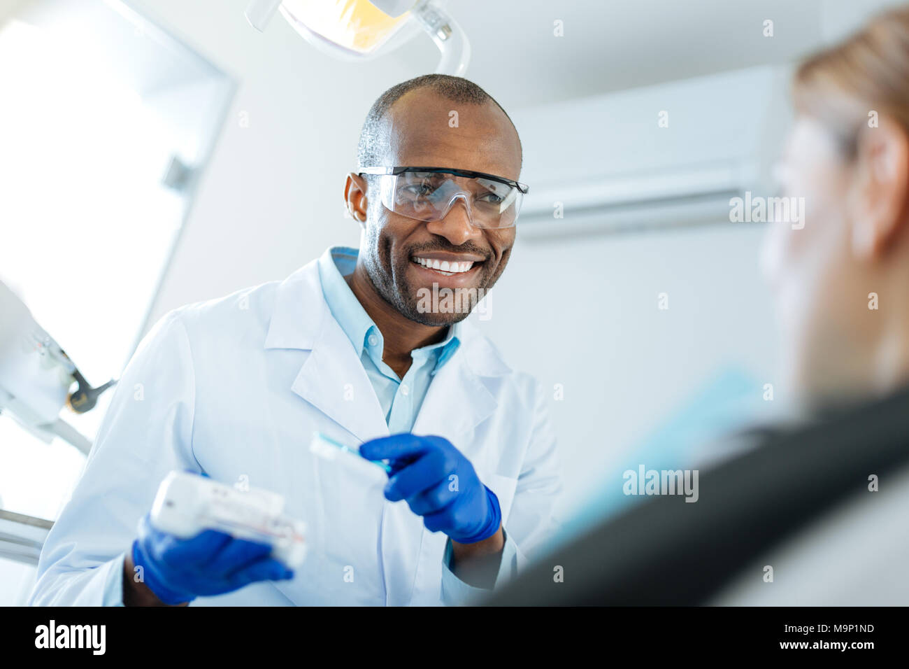 Pleasant dentist explaining how to prevent dental plaque Stock Photo ...