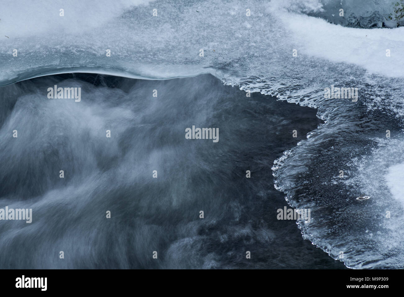 Rapidly flowing cold water through the ice Stock Photo - Alamy