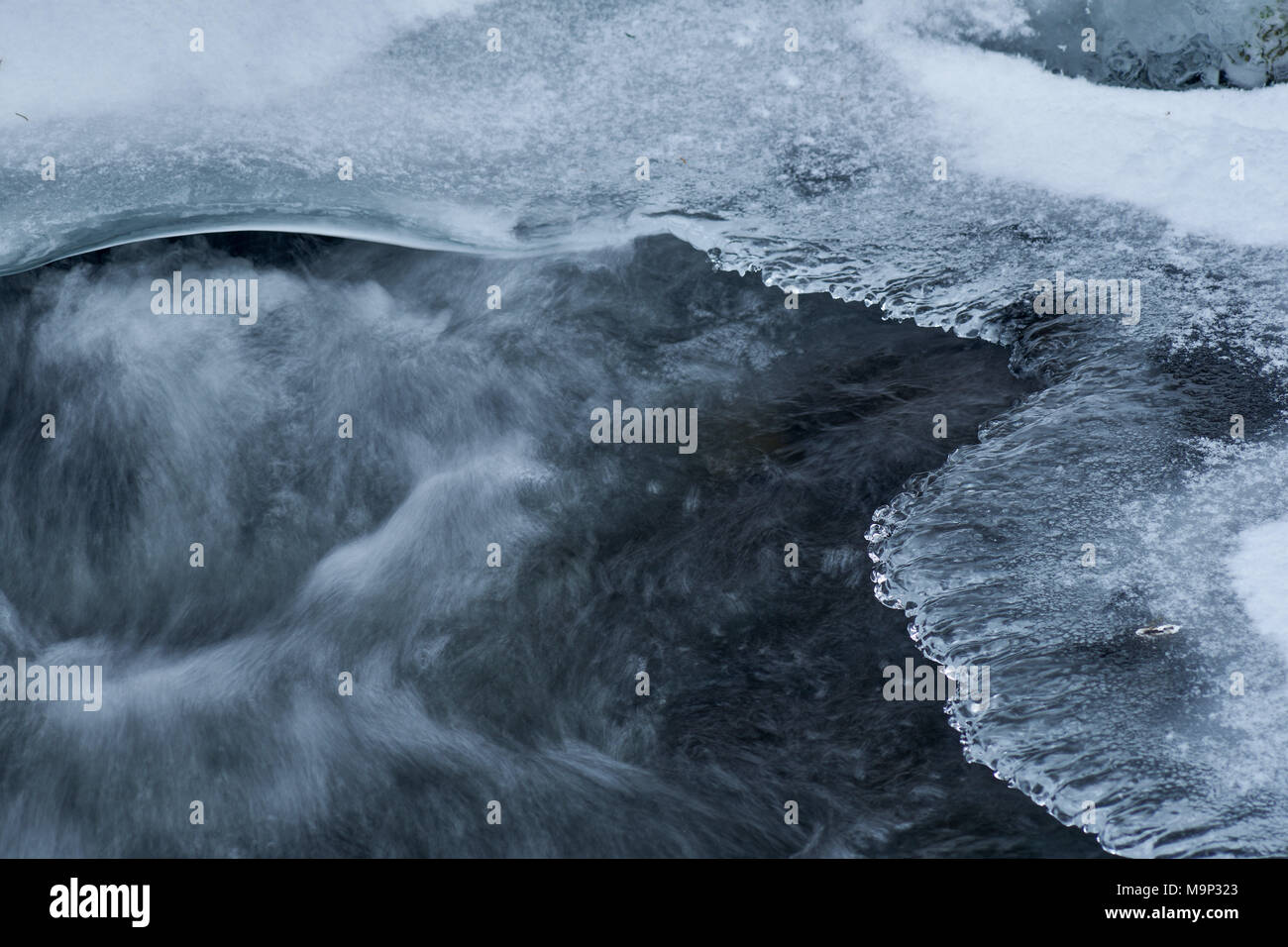 Rapidly flowing cold water through the ice Stock Photo - Alamy