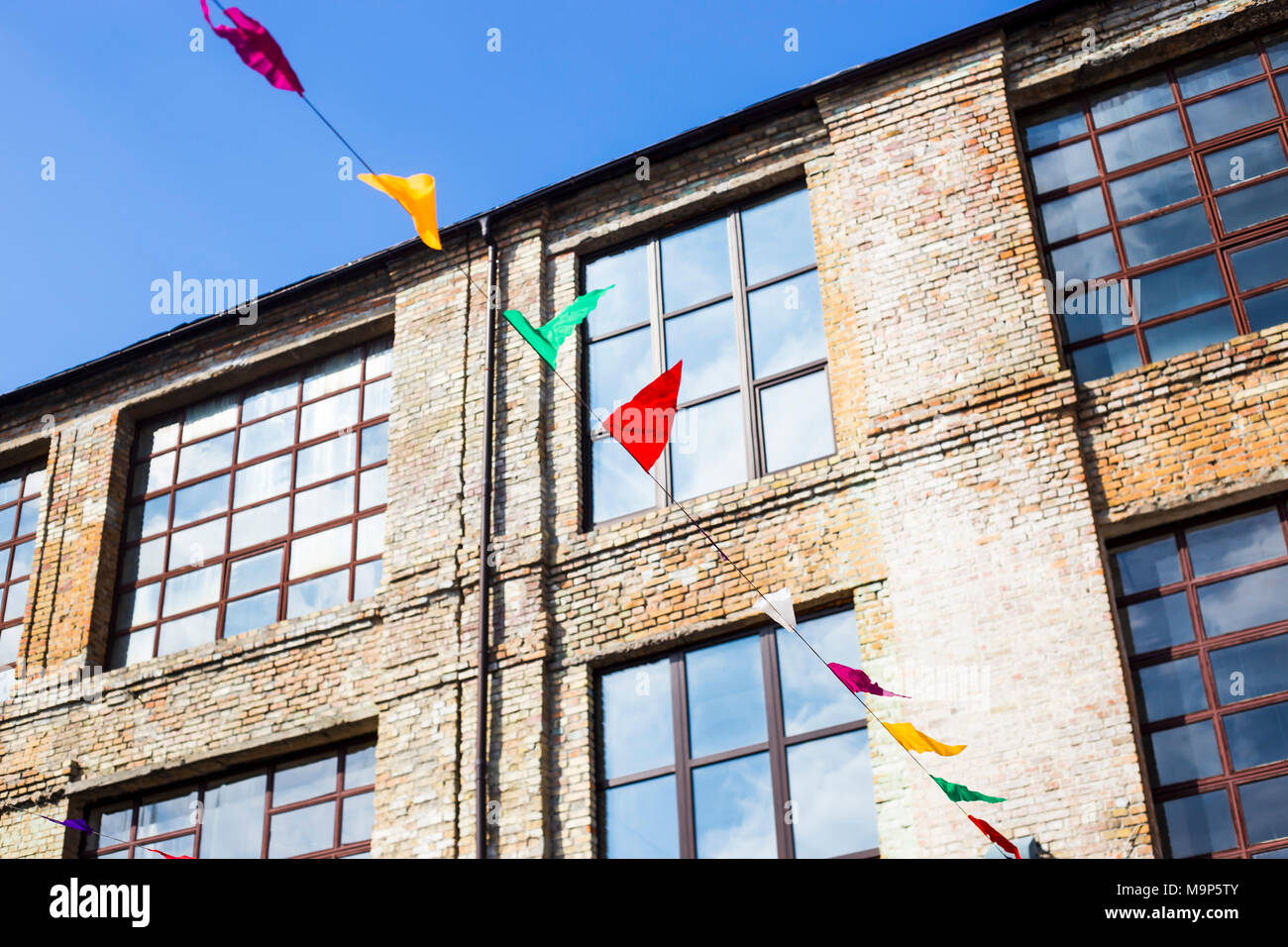 Multicolored triangular decorative flags hang on the background of old ...