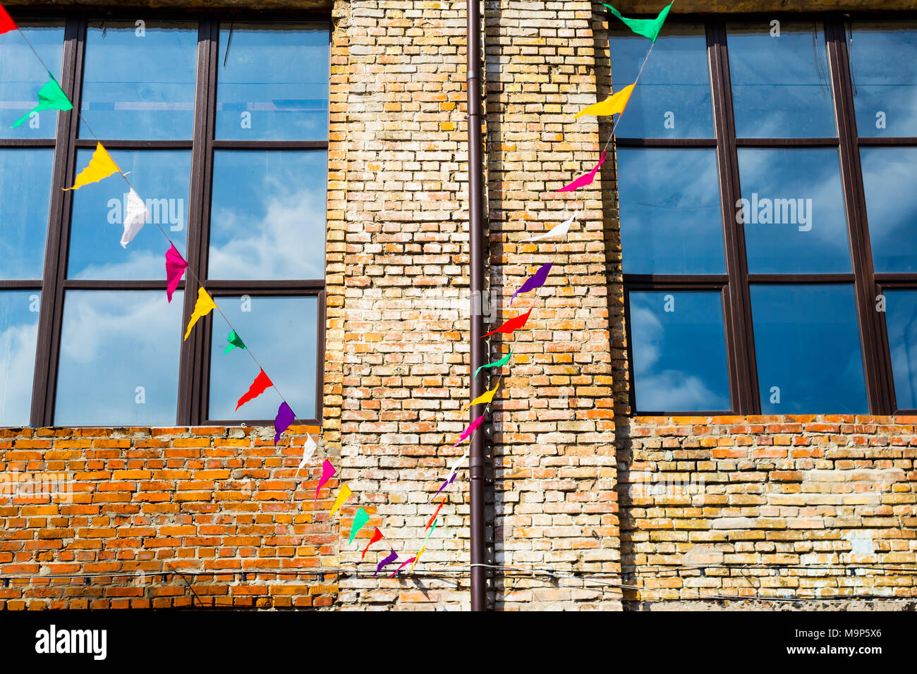 Multicolored triangular decorative flags hang on the background of old ...