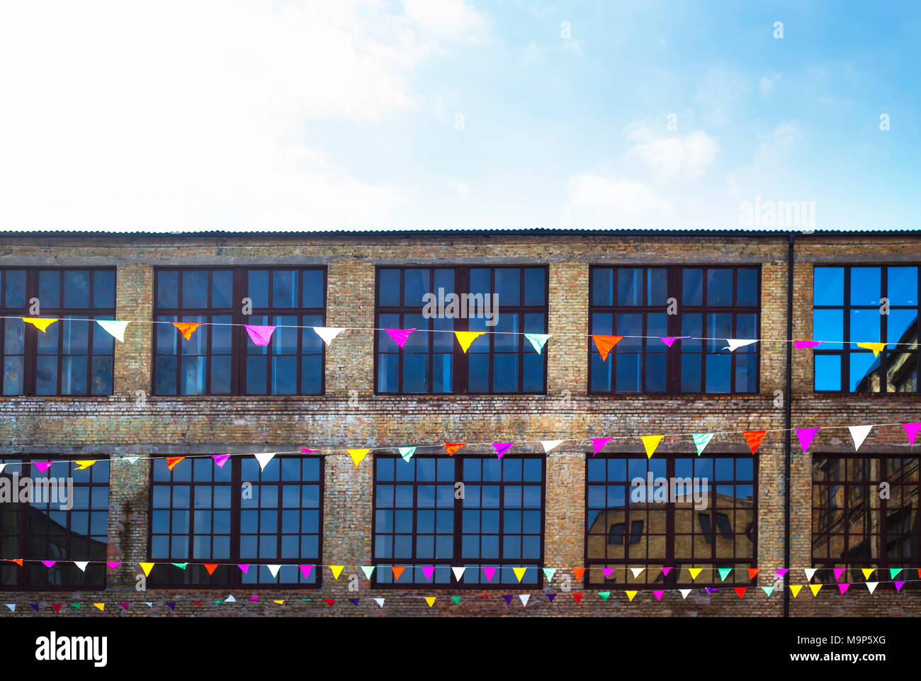 Multicolored triangular decorative flags hang on the background of old ...