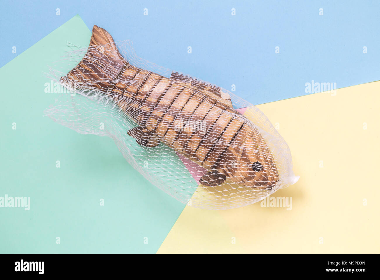 Wooden fish in fishing net on colorful pastel background minimal ...