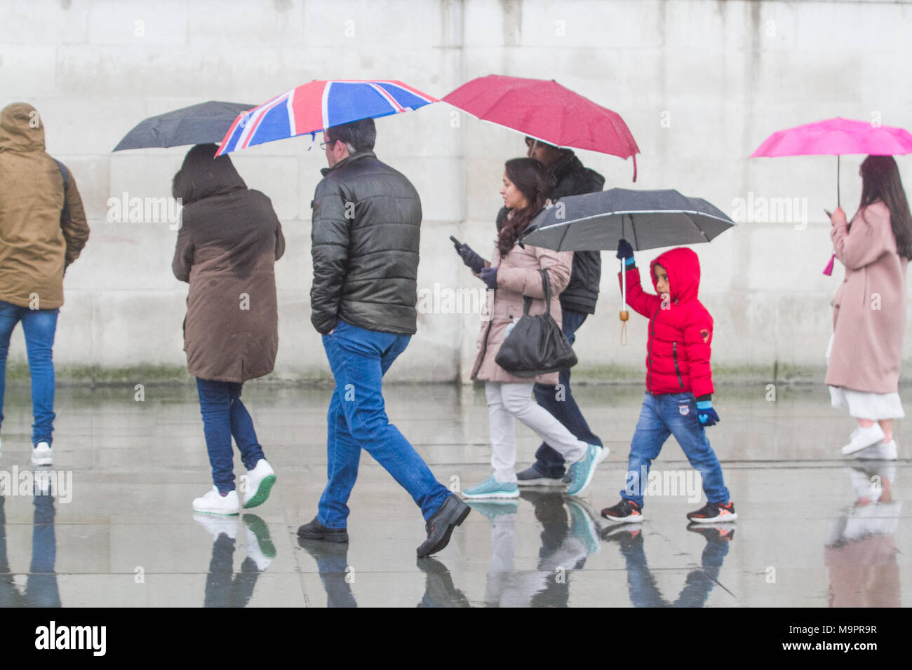 London UK. 28th March 2018. UK Weather: Pedestrians shelter form the ...