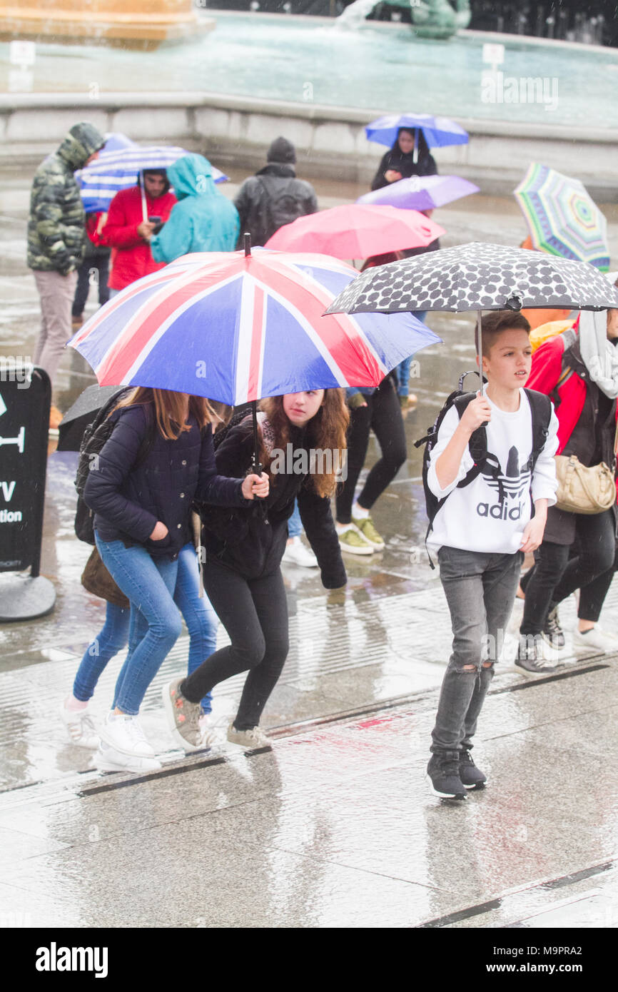 London UK. 28th March 2018. UK Weather: Pedestrians shelter form the ...