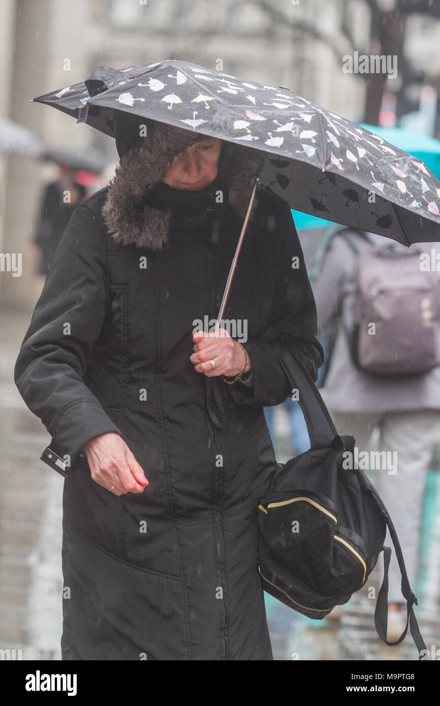 London UK. 28th March 2018. Pedestrians shelter from the cold freezing ...