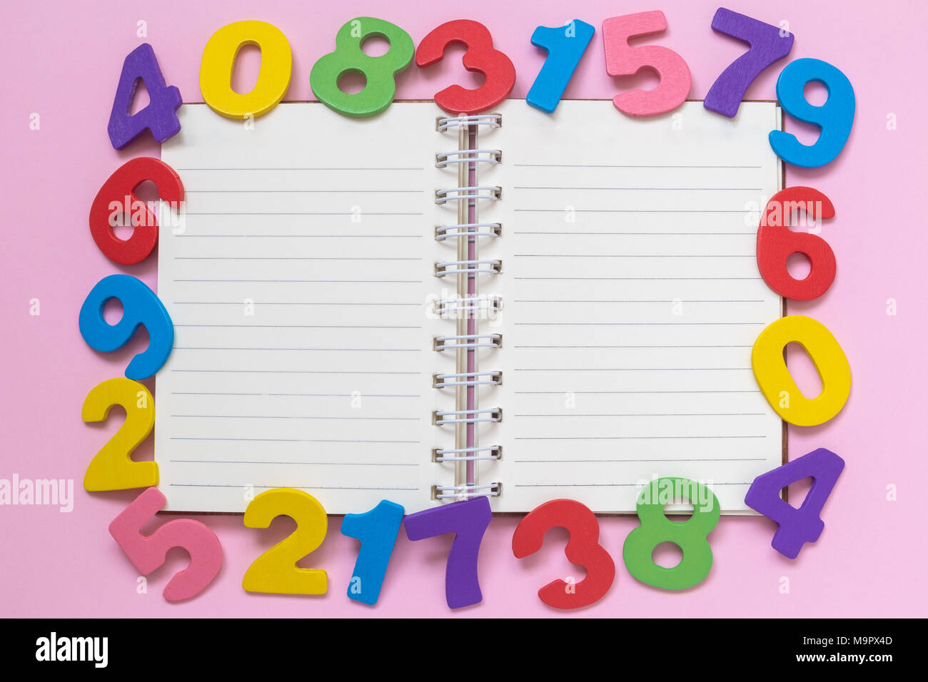 Open notepad and colorful numbers against pastel pink background flat ...