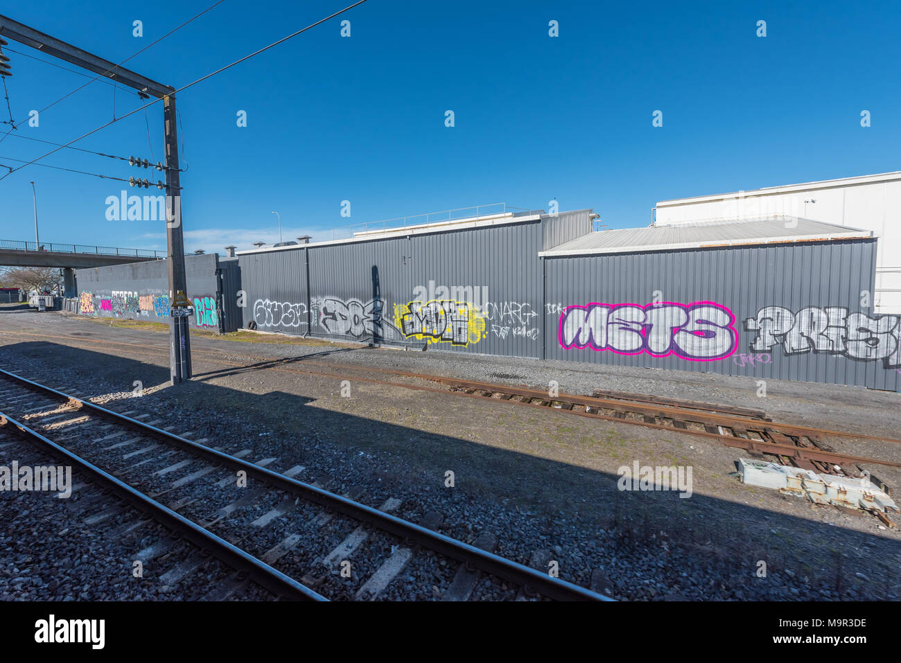 Graffiti on walls alongside an electrified railway track in New Zealand ...