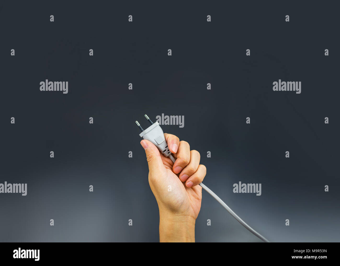 Plug hand holding on black background Stock Photo - Alamy