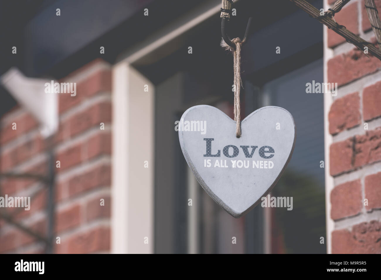 Decorative heart hanging on the wall outside of brick house. Love cozy ...