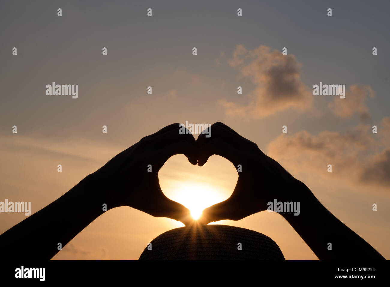 silhouette Hands are making a heart shape to let the sun pass through ...