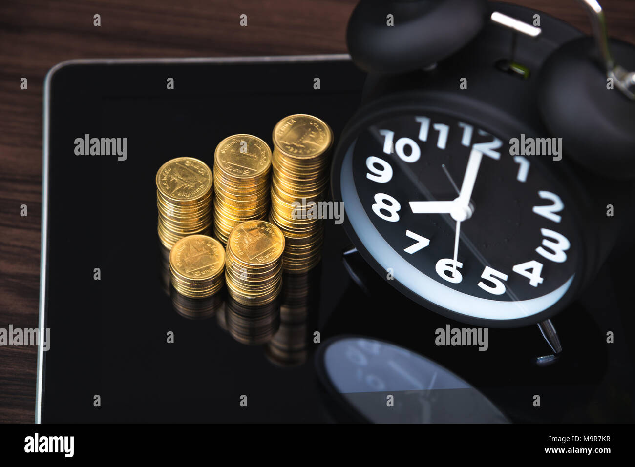 Coins stacks and alarm clock with tablet computer and financial graph ...