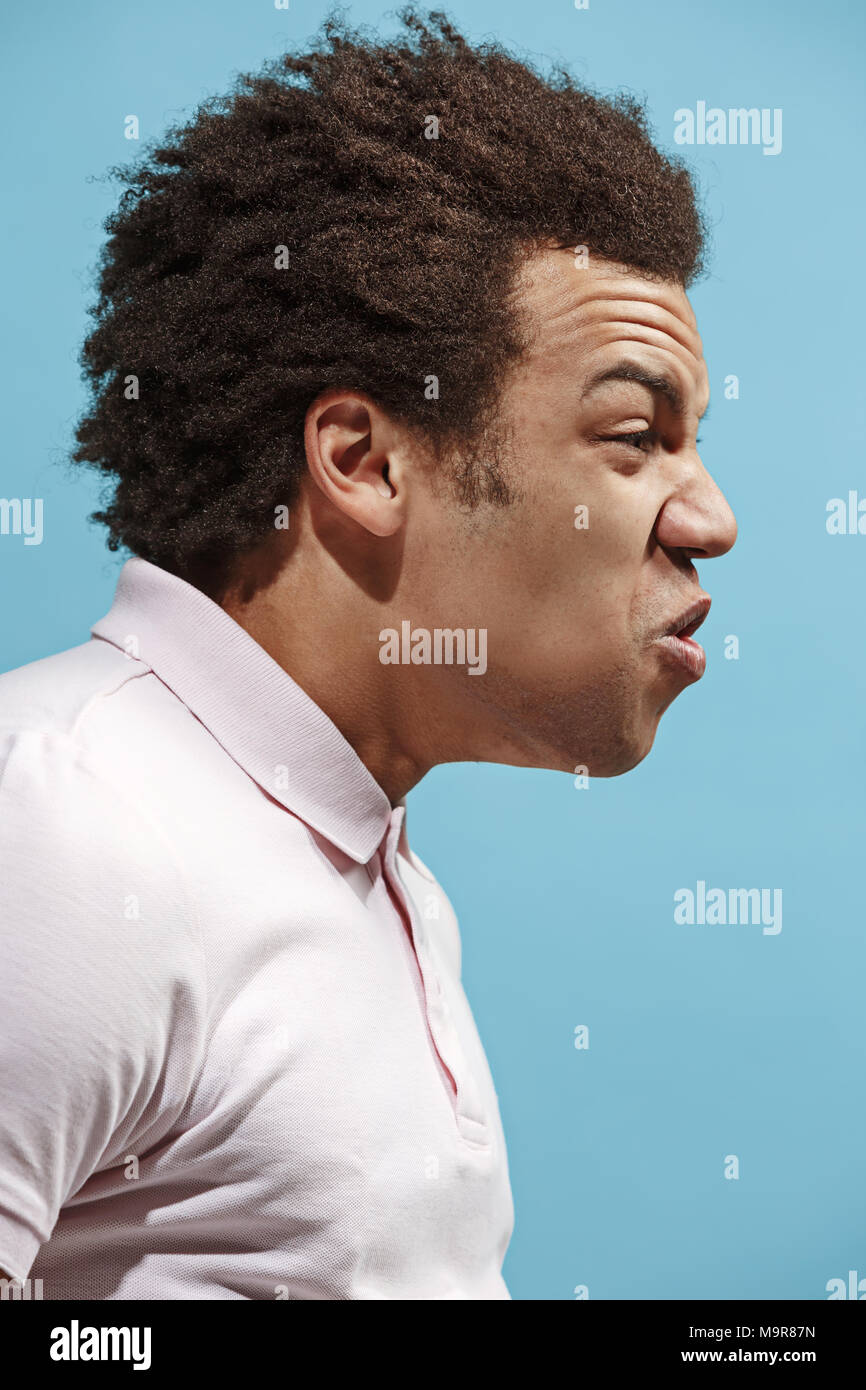 The young emotional angry man screaming on blue studio background Stock ...