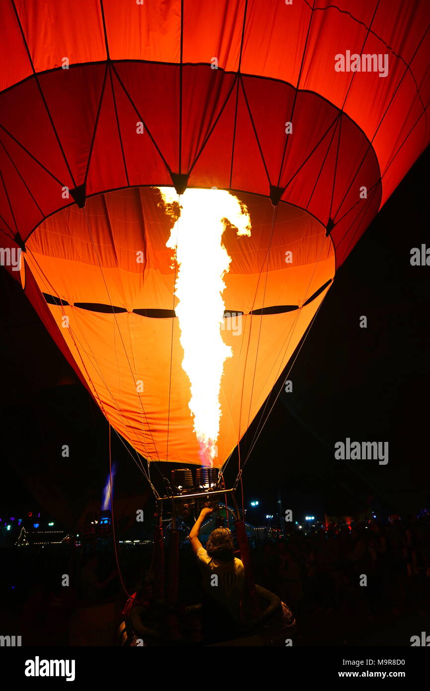 Man filling the orange balloon with hot air. View of the flame inside ...