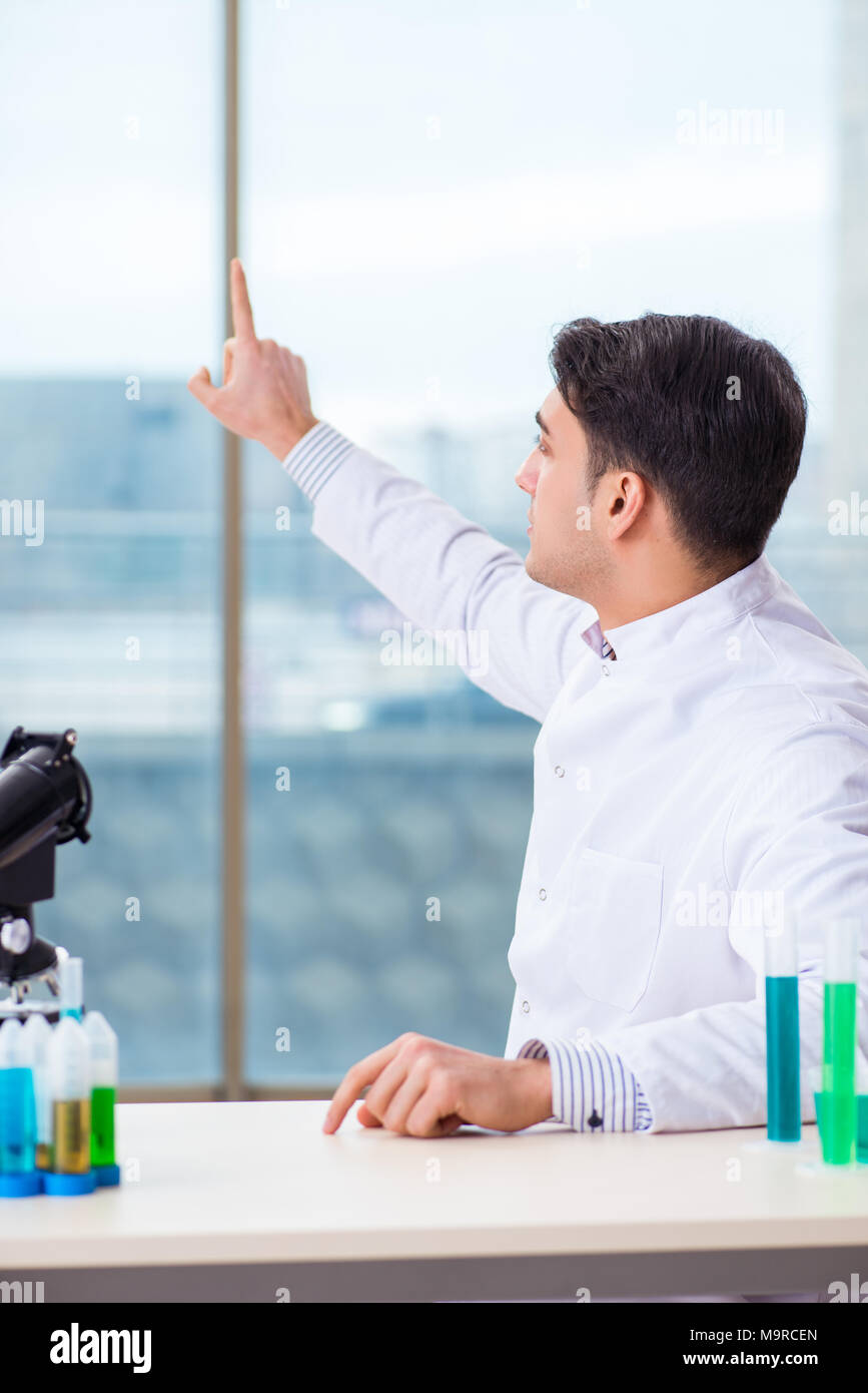 Young chemist pressing virtual buttons in lab Stock Photo - Alamy