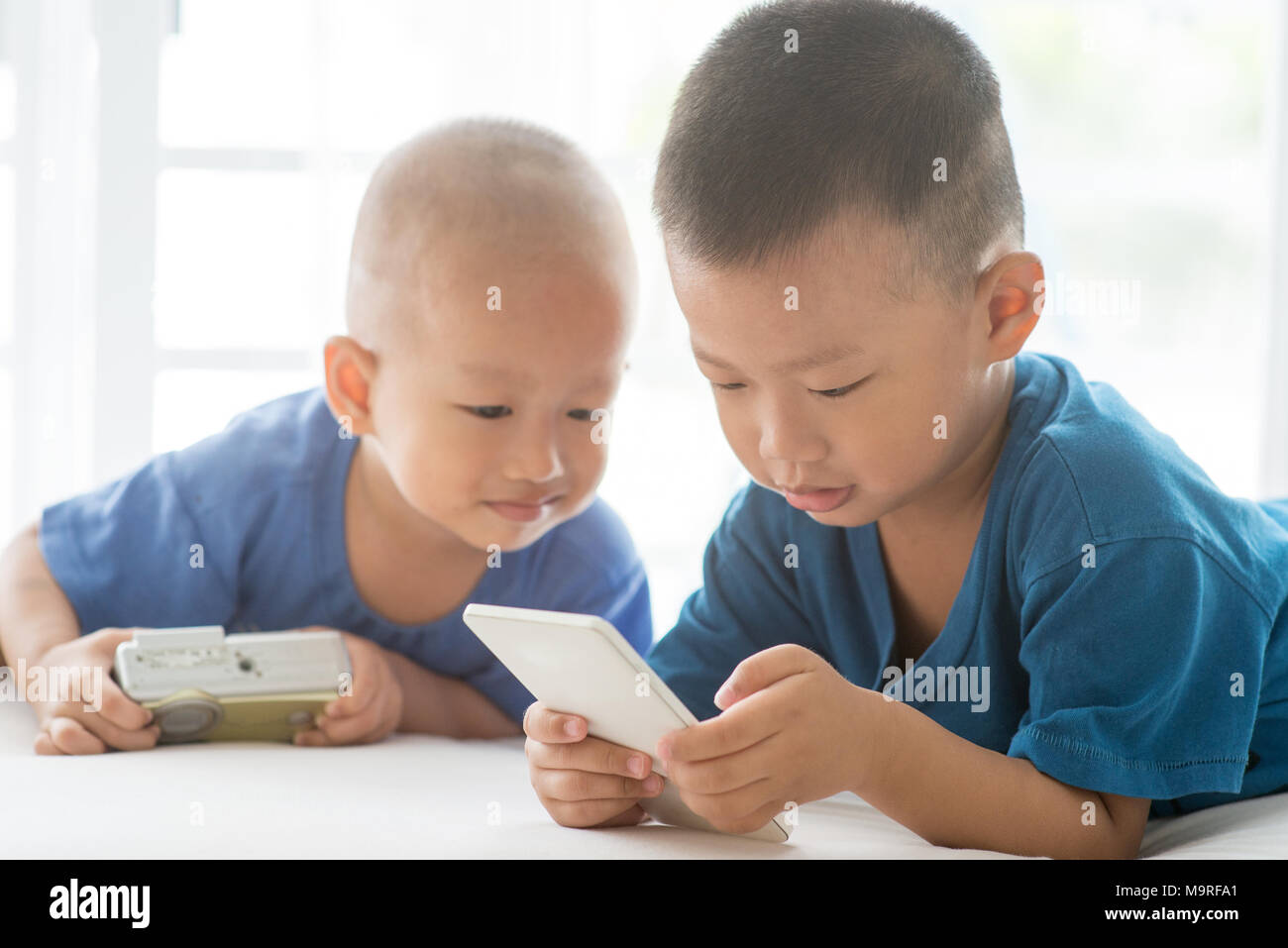 Young children addicted to technology gadget. Asian boys using ...