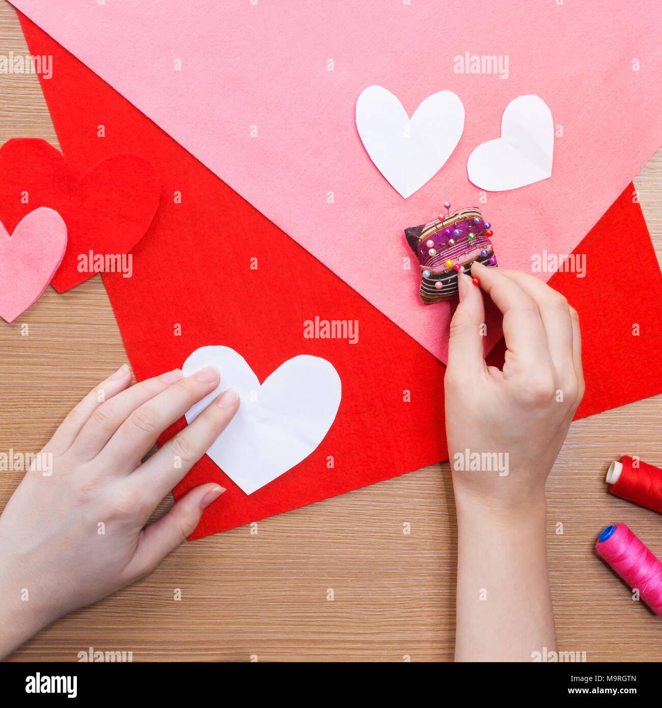 top view of hands pinning heart pattern felt fabric. sewing tools Stock ...