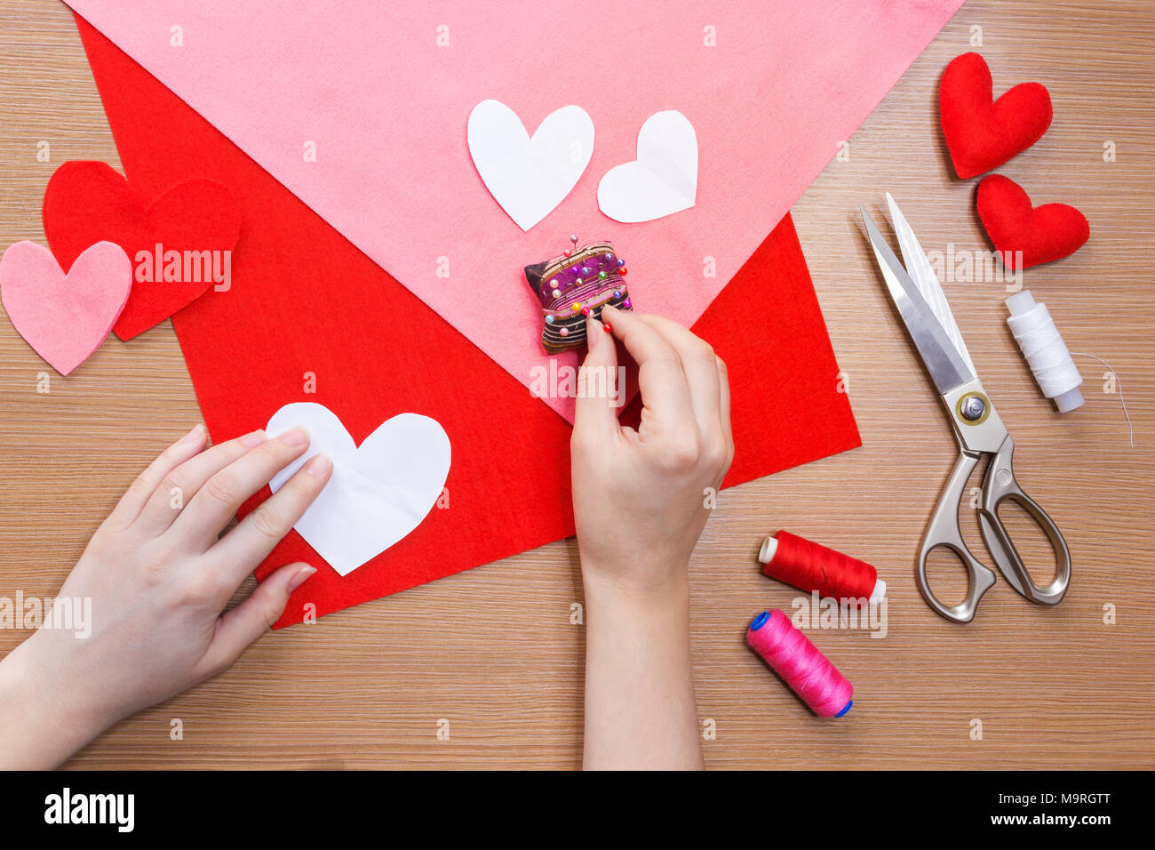 top view of hands pinning heart pattern felt fabric. sewing tools Stock ...