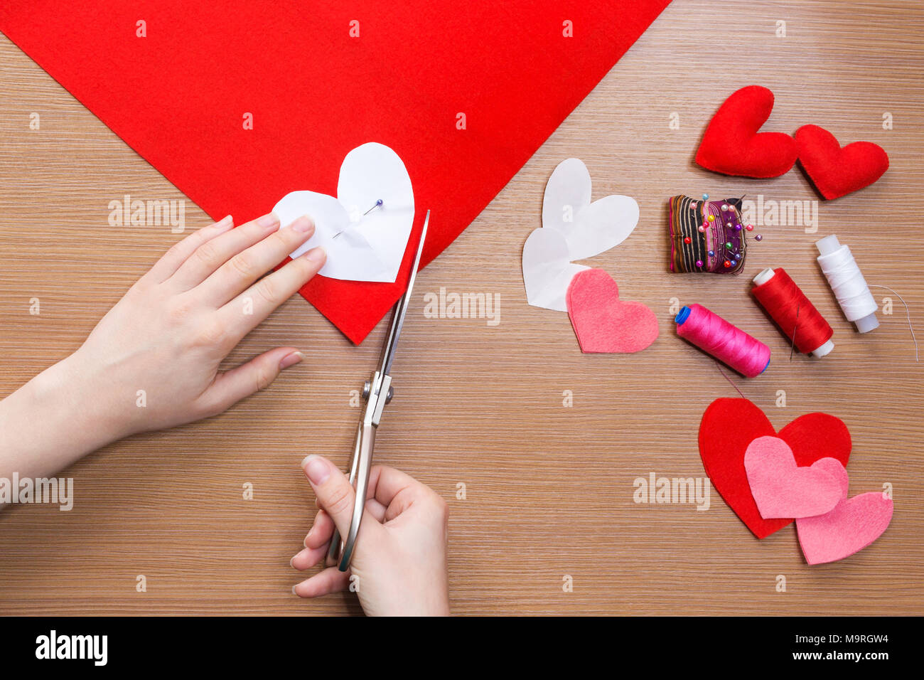 top view of hands cutting heart pattern from felt fabric. sewing tools ...