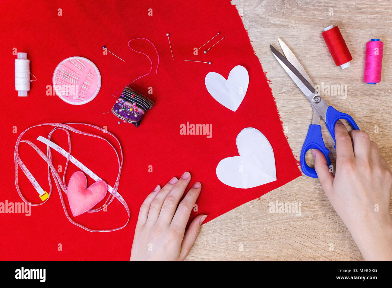 top view of hands cutting heart pattern from felt fabric. sewing tools ...