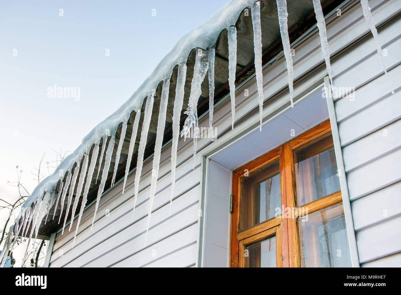 big icicles on a house roof, winter evening Stock Photo - Alamy