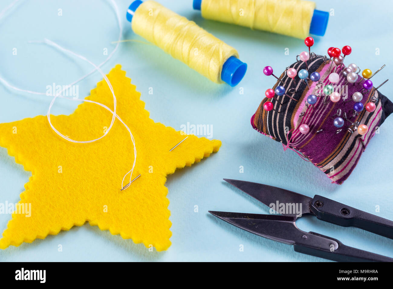 sewing star figures from yellow felt, materials on a light blue ...
