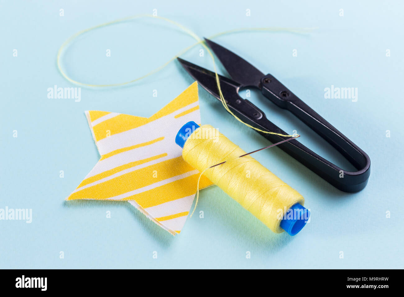 sewing star figures from yellow felt, materials on a light blue ...