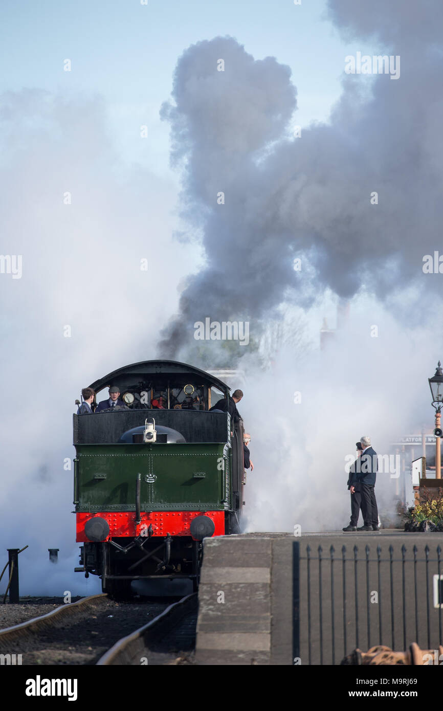 Rear view close up of vintage UK steam locomotive letting off steam as ...