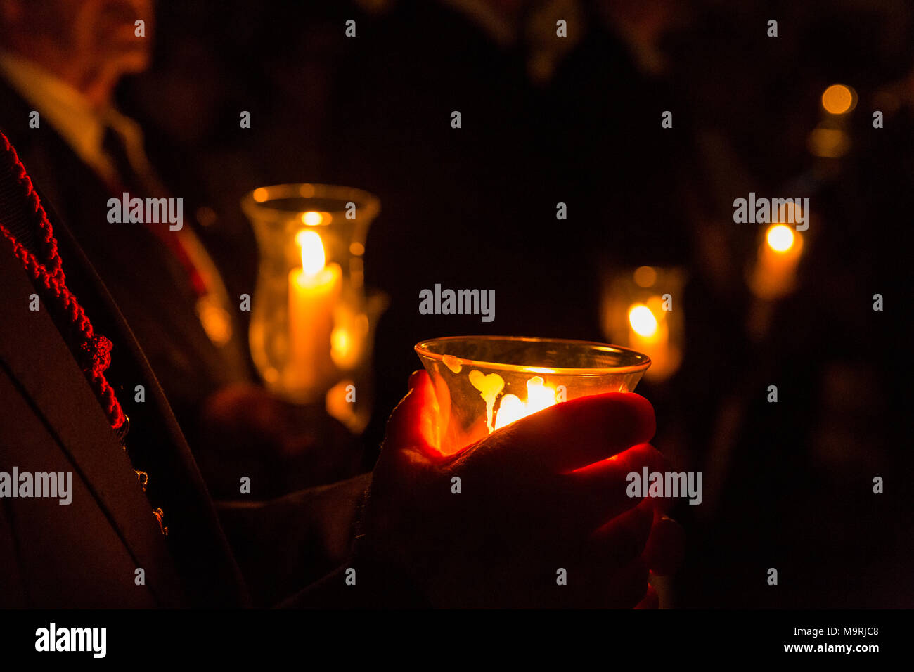 Candlelit faces and hands of catholic men in a holy week procession in ...