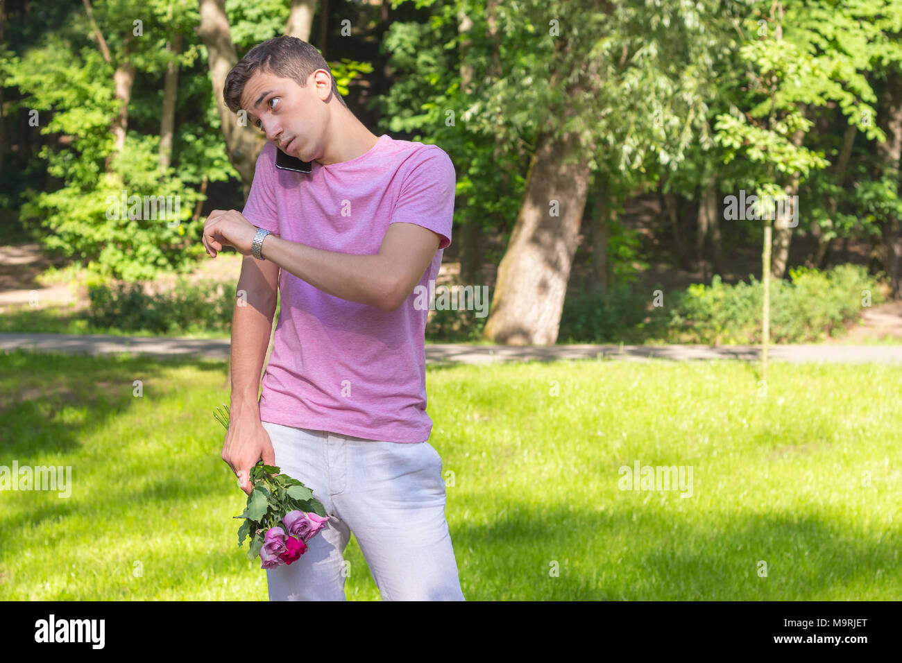 young men waiting date with roses watching time and calling Stock Photo ...