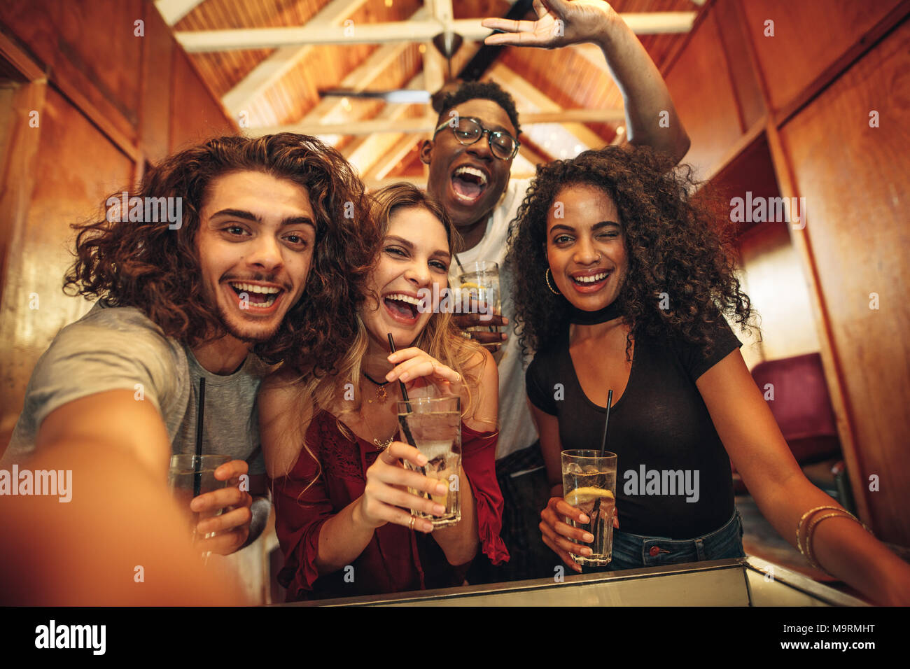 Group of happy young friends with drinks gathered for party in club ...