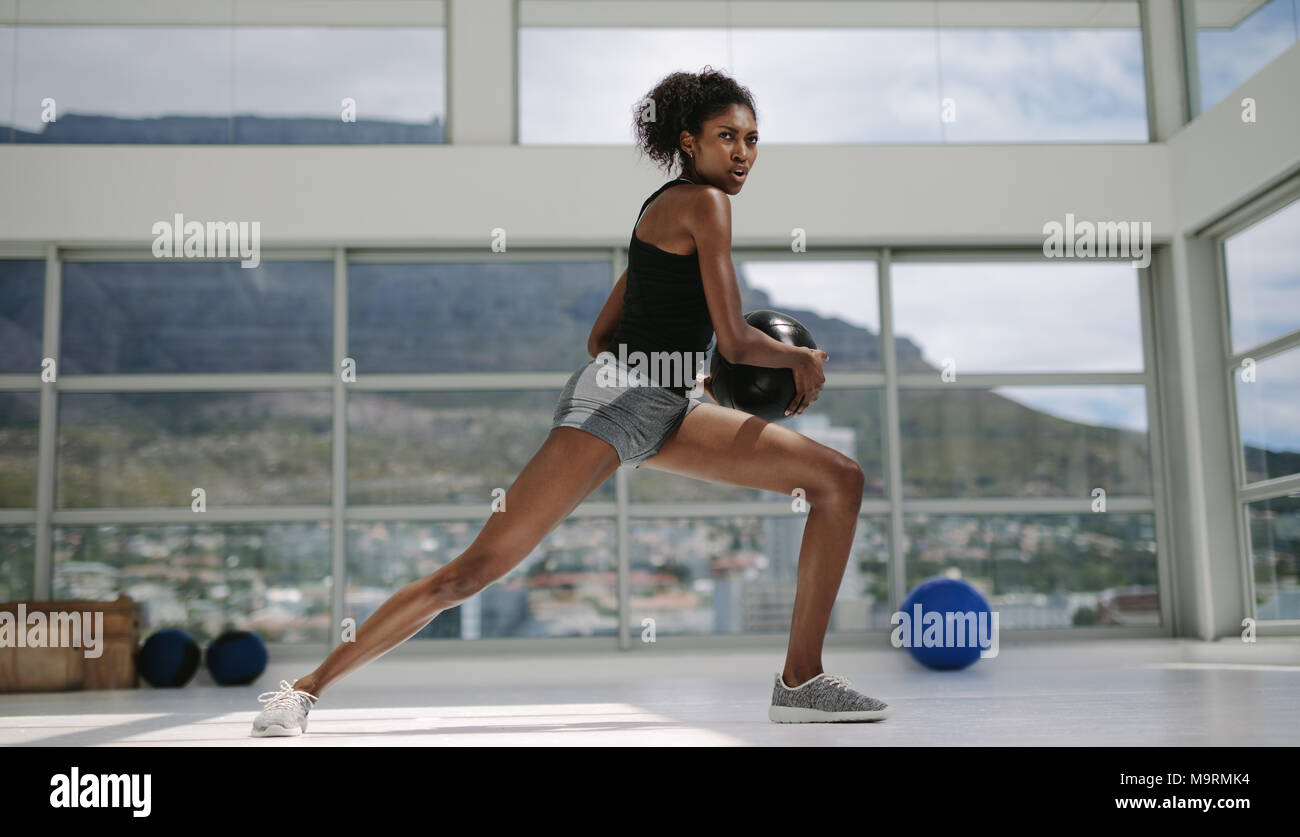 African slim girl doing stretching exercise with medicine ball. Woman ...